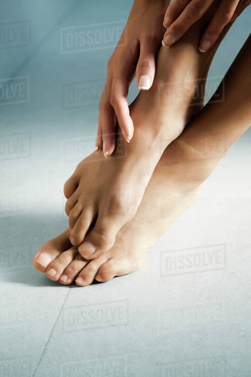 Woman's hand touching her bare feet - Royalty-free Stock Photo | Dissolve
