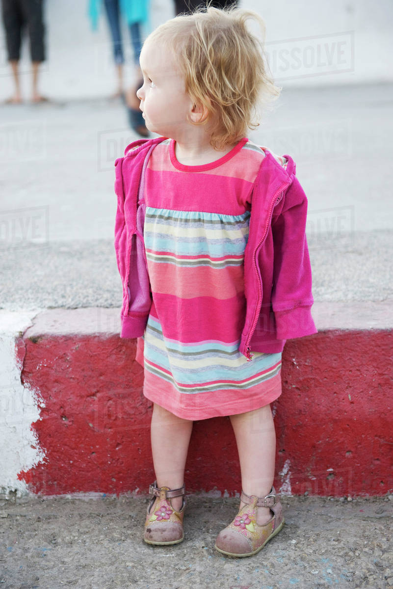 Toddler girl standing on sidewalk, looking over her shoulder - Royalty ...