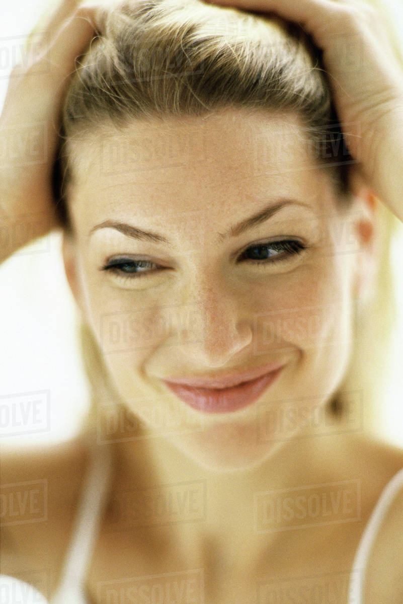 Woman pulling hair back, portrait - Royalty-free Stock Photo | Dissolve