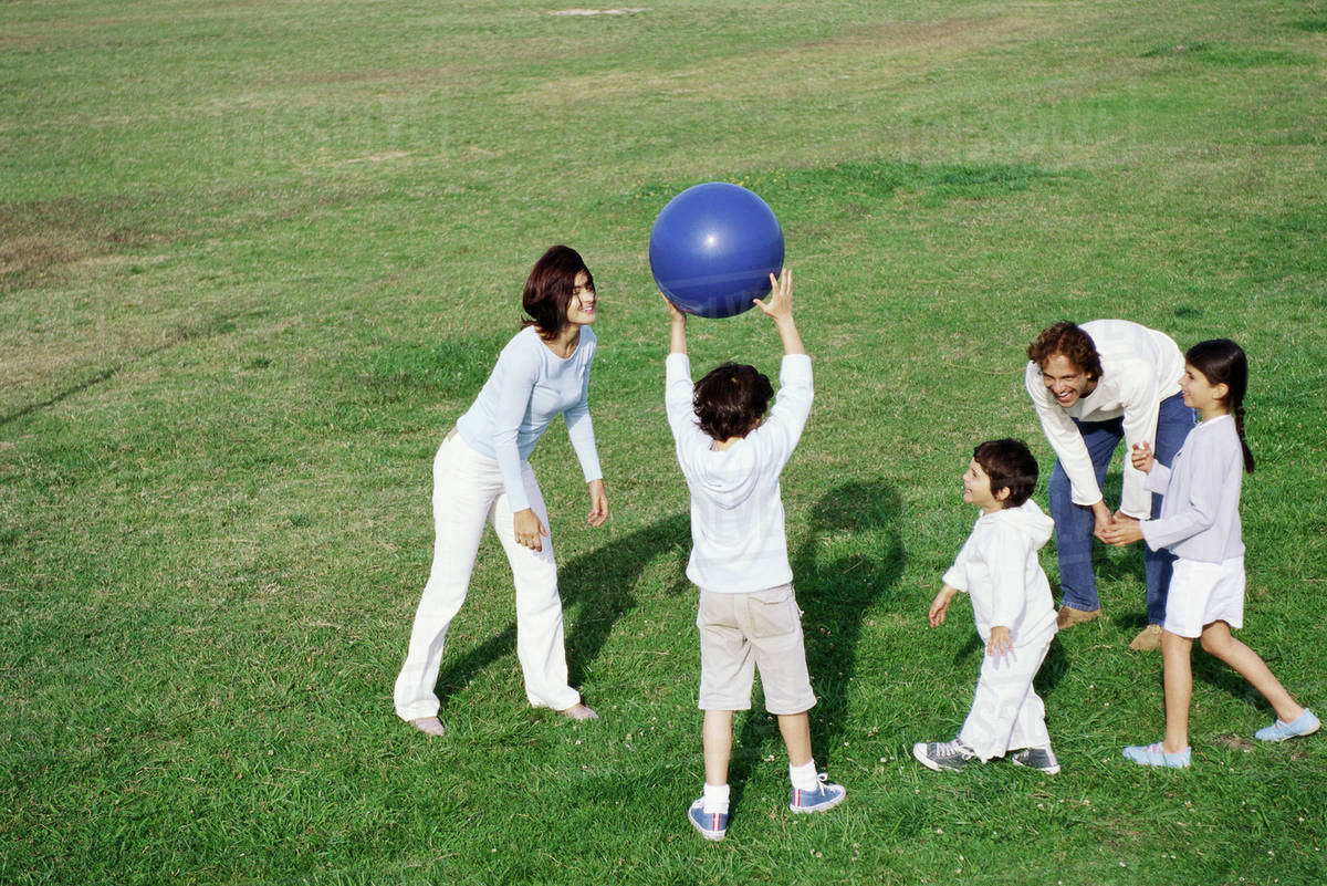Family playing with ball in grassy field - Royalty-free Stock Photo ...