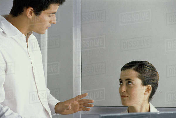 Man standing, talking to female colleague - Royalty-free Stock Photo ...