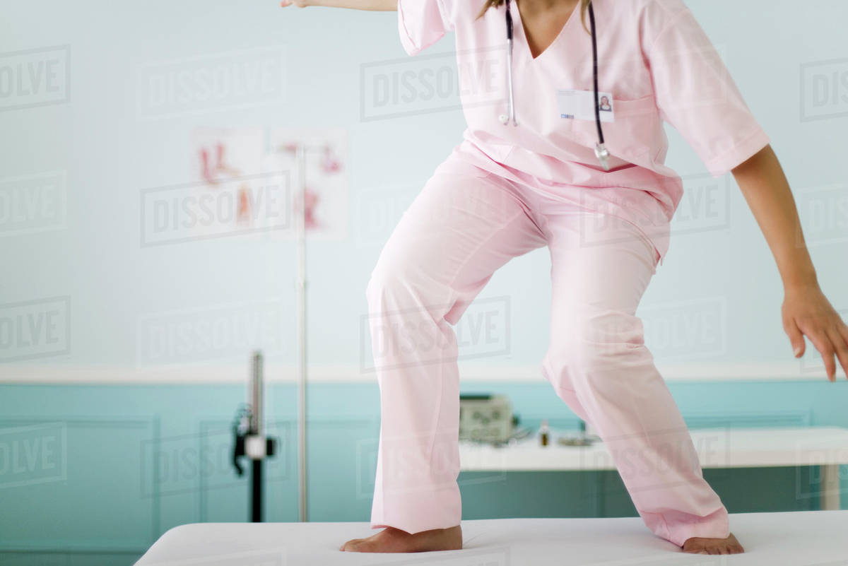 Nurse balancing on top of examination table, cropped - Royalty-free ...