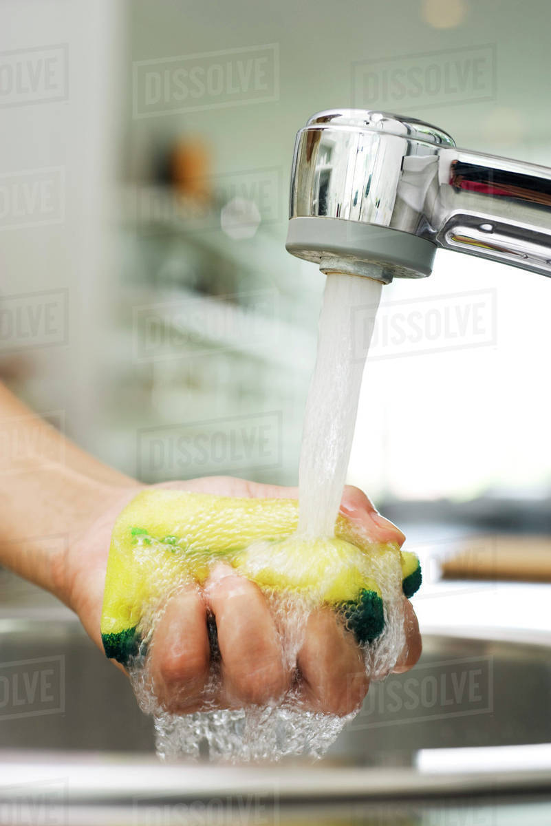 Person rinsing sponge under kitchen faucet - Royalty-free Stock Photo ...