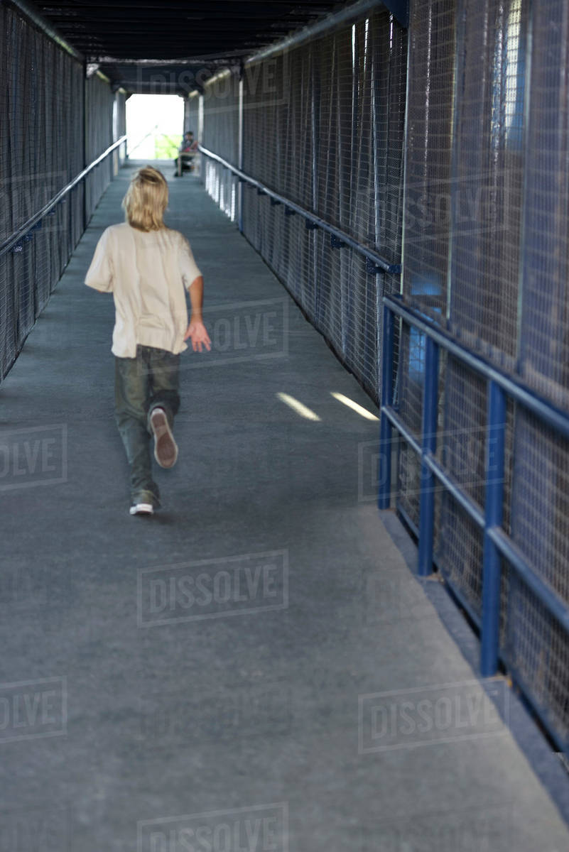 Boy running down corridor, rear view - Stock Photo - Dissolve
