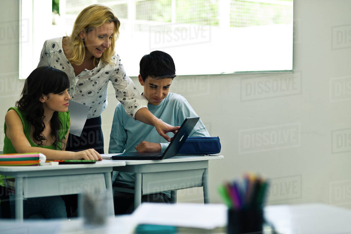 Teacher helping students using laptop computer in class - Stock Photo ...