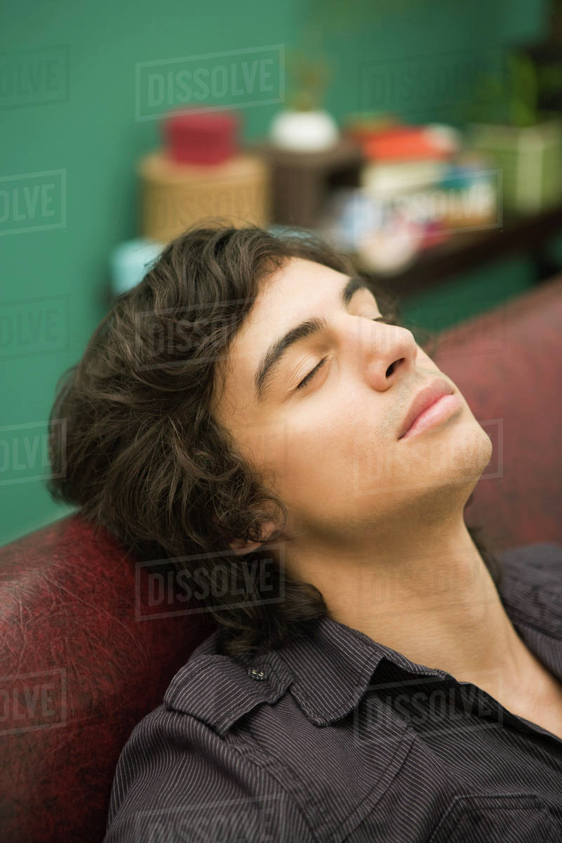 Young man resting on sofa with eyes closed - Royalty-free Stock Photo ...