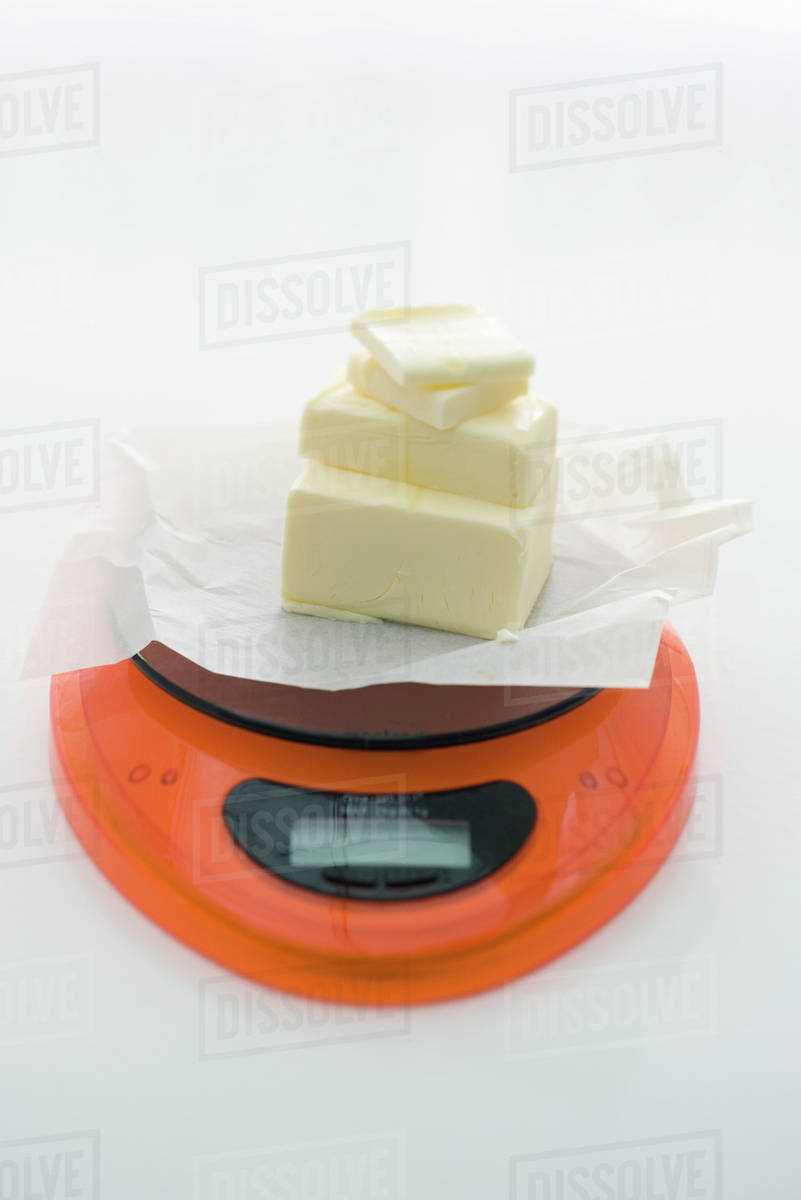 Weighing butter on kitchen scale - Stock Photo - Dissolve