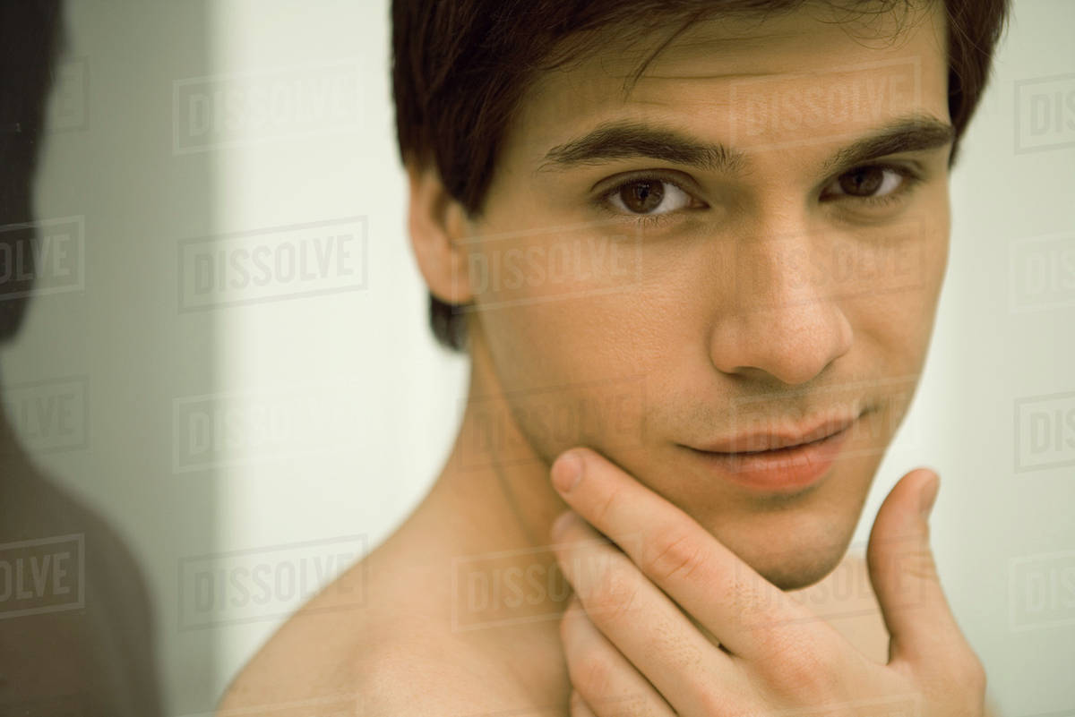 Young man touching chin, smiling at camera - Royalty-free Stock Photo | Dissolve