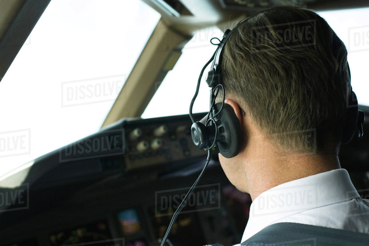 Pilot wearing headphones, rear view, close-up - Stock Photo - Dissolve