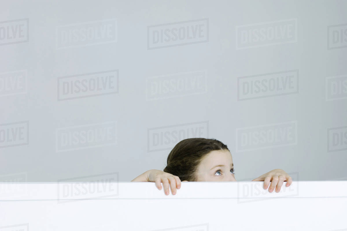 Little girl peeking over ledge - Royalty-free Stock Photo | Dissolve