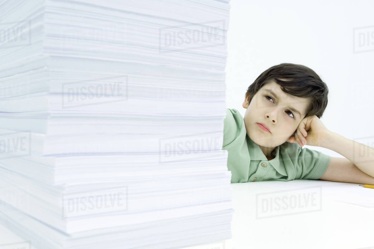 Boy looking at tall stack of homework, frowning - Royalty-free Stock ...