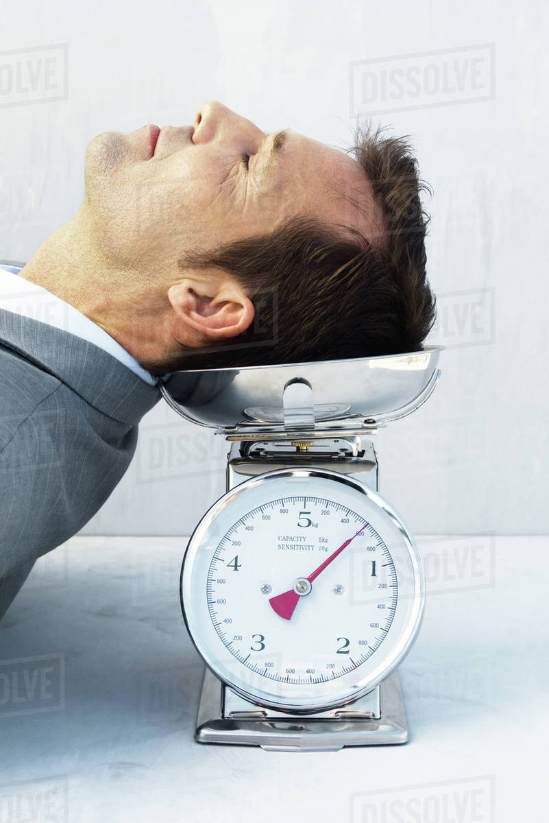 Man resting head on scale, eyes closed - Stock Photo - Dissolve