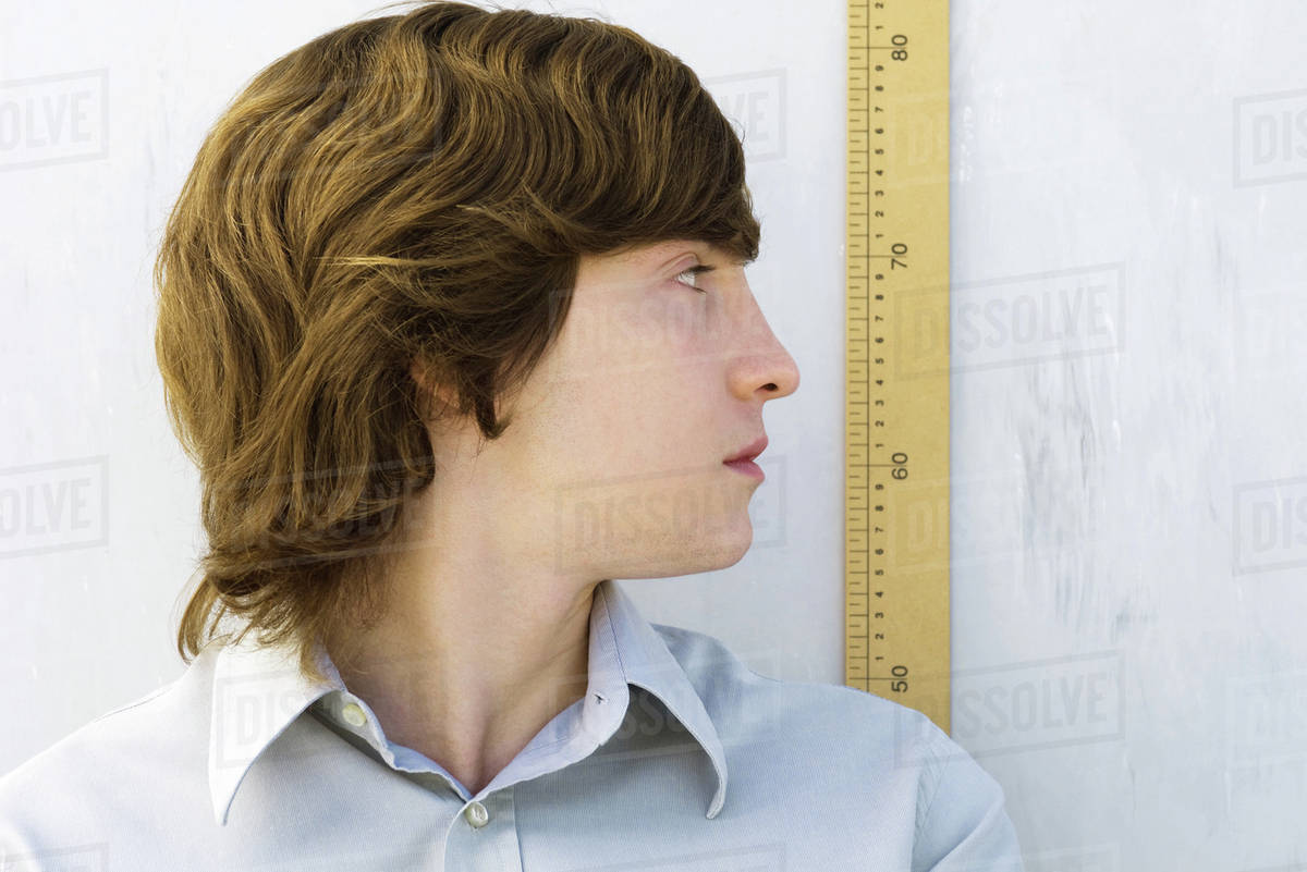 Young man looking over shoulder at yardstick, close-up - Stock Photo ...