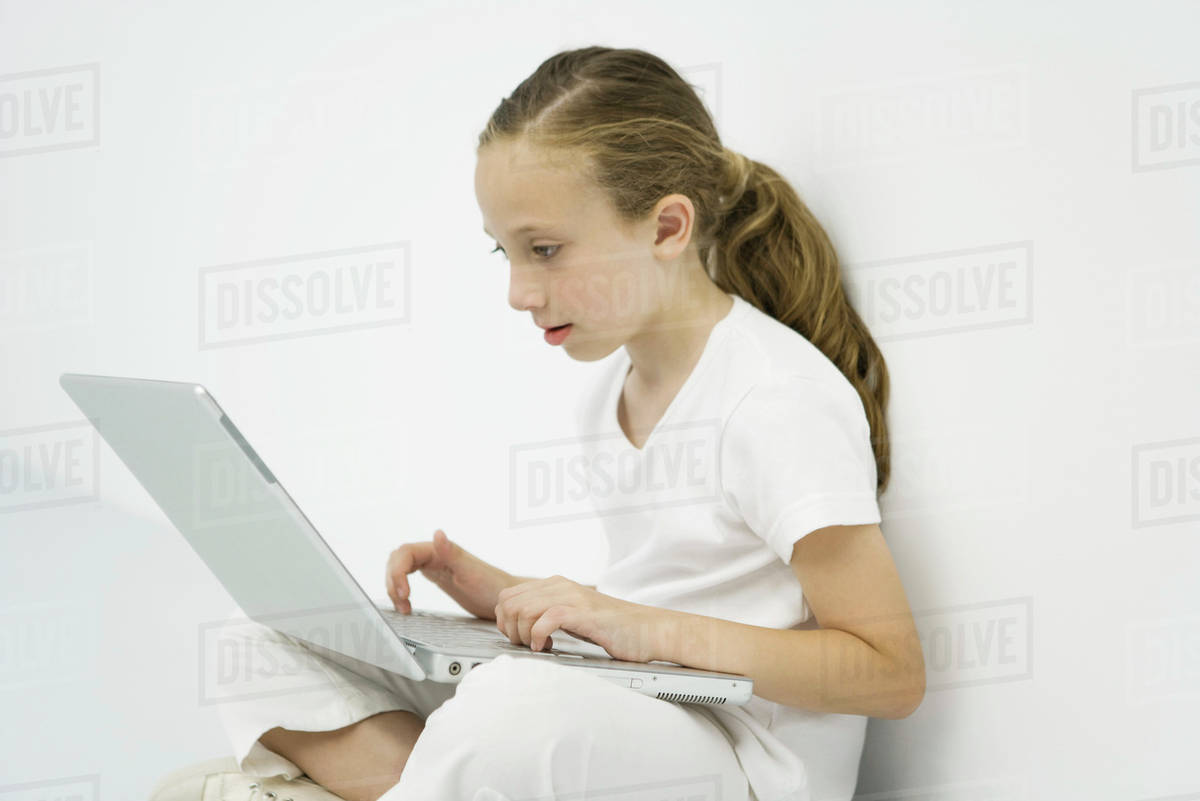 Little girl using laptop computer, side view - Stock Photo - Dissolve