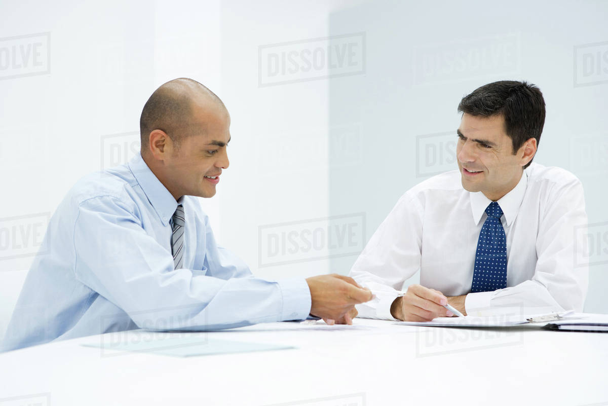 Two businessmen sitting at table, discussing document - Royalty-free ...