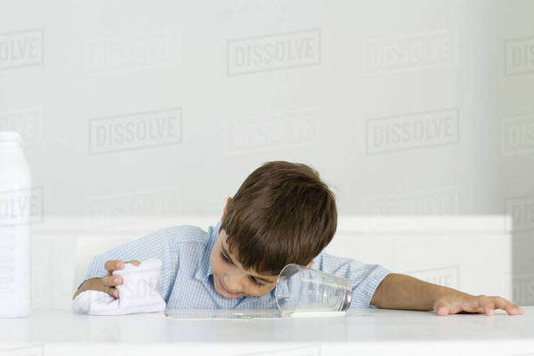 Boy wiping up spilled milk with towel - Royalty-free Stock Photo | Dissolve
