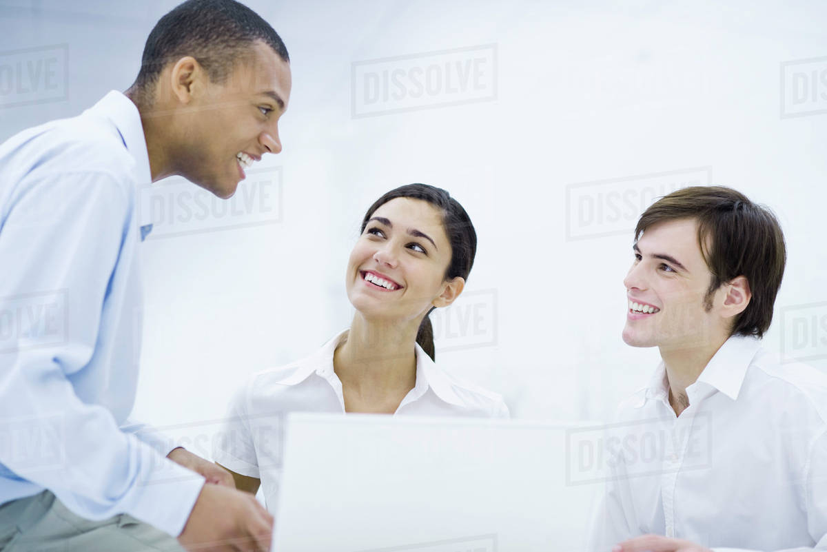 Young professionals smiling at each other, sitting near laptop ...