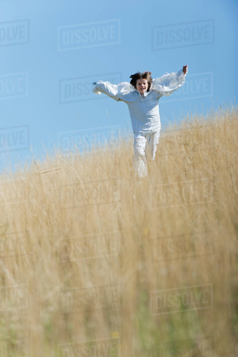 Boy running through tall grass - Stock Photo - Dissolve