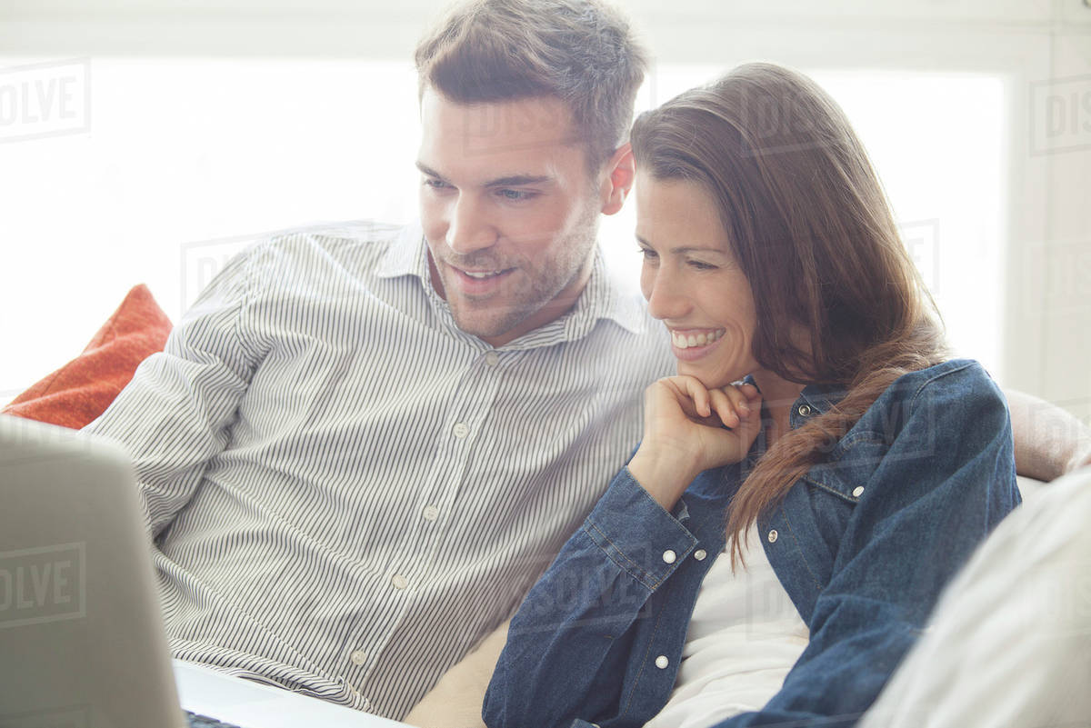 Couple relaxing at home looking at laptop computer together - Royalty ...