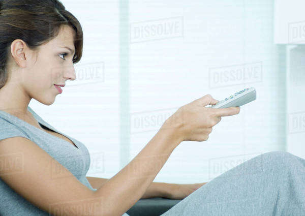 Young woman pointing remote control, profile - Stock Photo - Dissolve