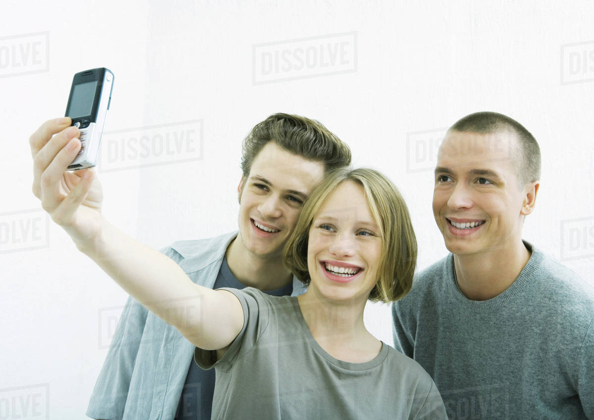 Three young friends taking photo together with cell phone - Royalty ...