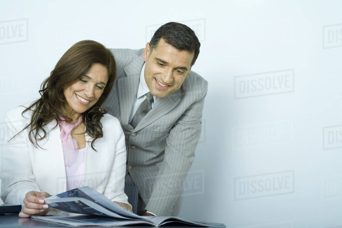 Mature business colleagues looking at magazine together - Stock Photo ...