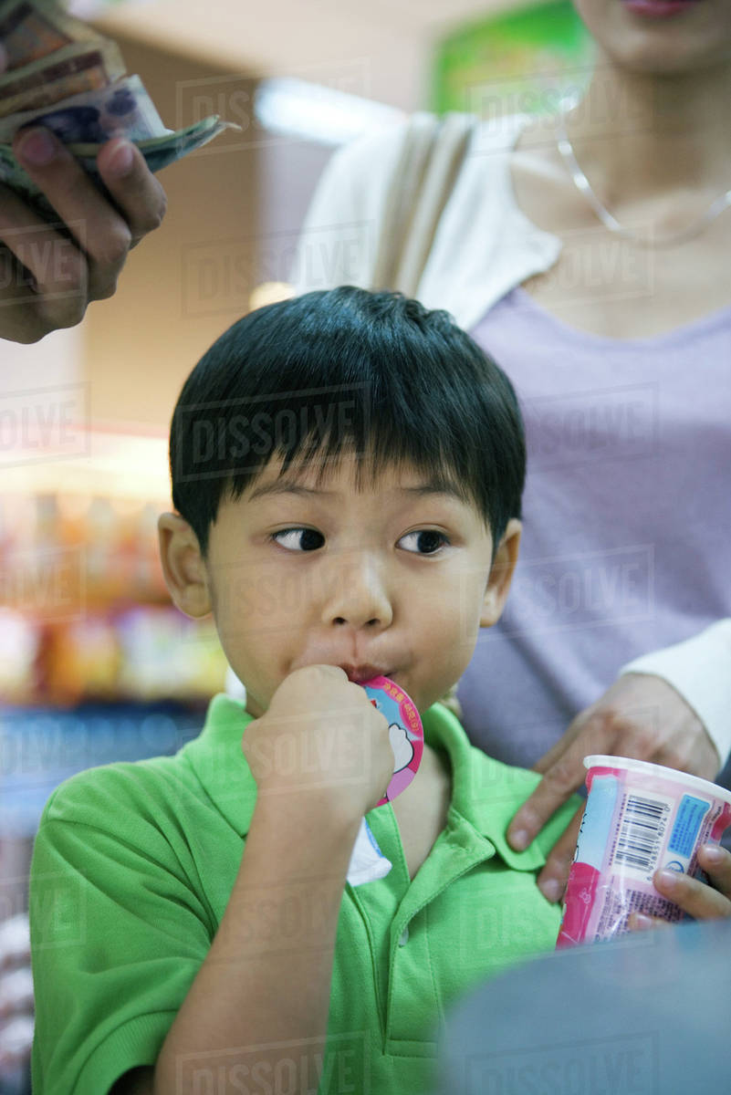 Boy eating sweet snack at checkout counter - Stock Photo - Dissolve