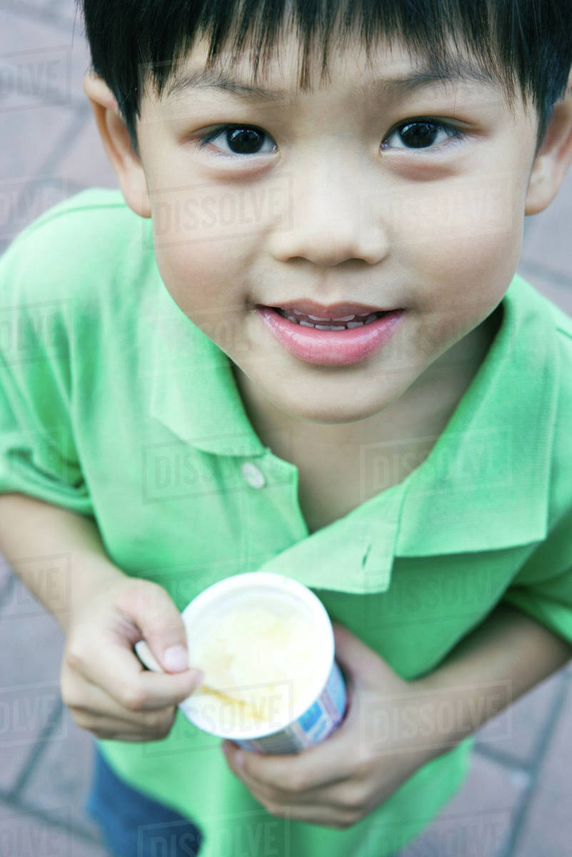 Boy holding sweet snack, smiling at camera - Stock Photo - Dissolve