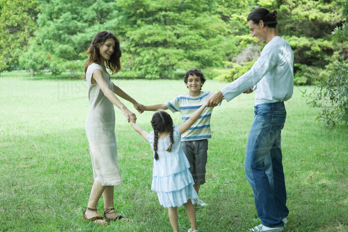 Family outdoors playing ring-around-the-rosy - Stock Photo - Dissolve