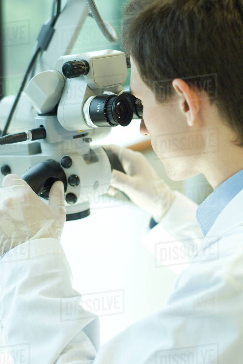 Young male scientist looking through microscope - Royalty-free Stock ...