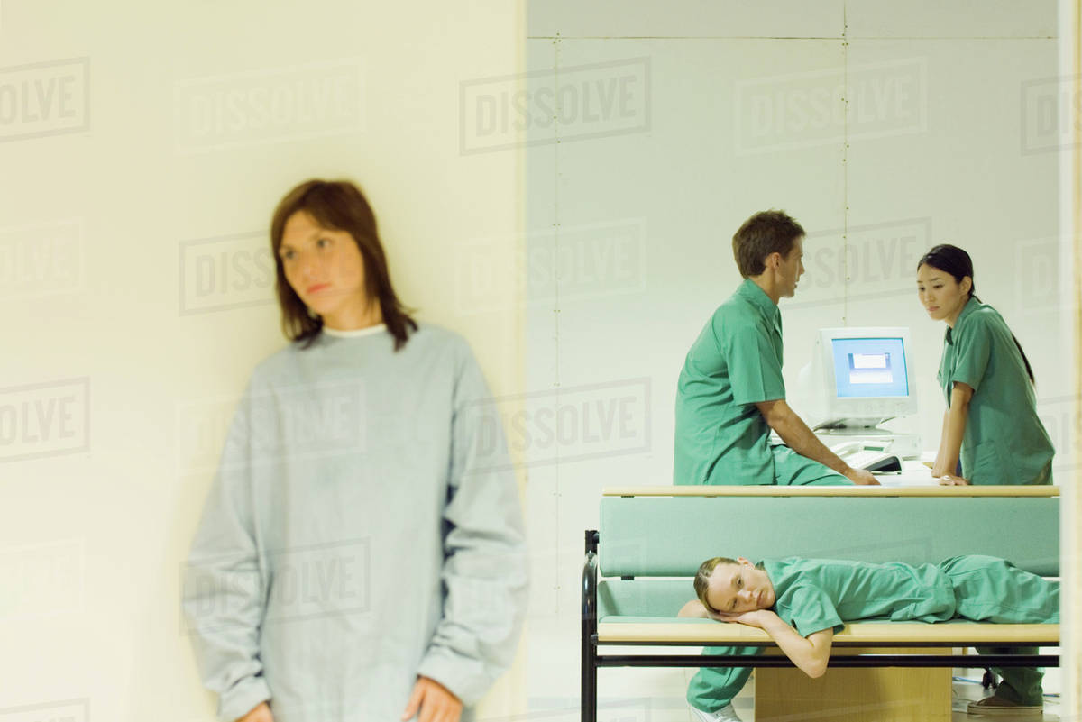 Medical workers chatting in office, one lying down on bench, female ...