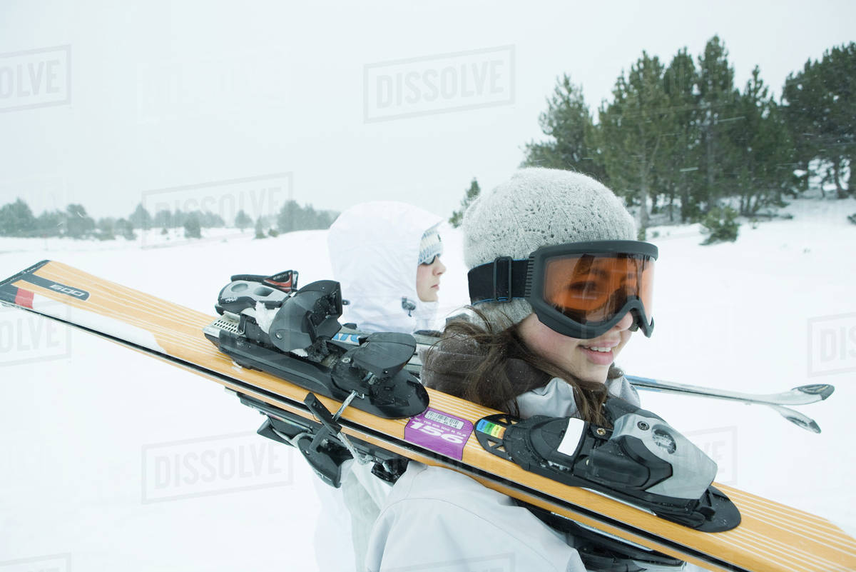 Two young skiers walking together, carrying skis on shoulders - Royalty ...