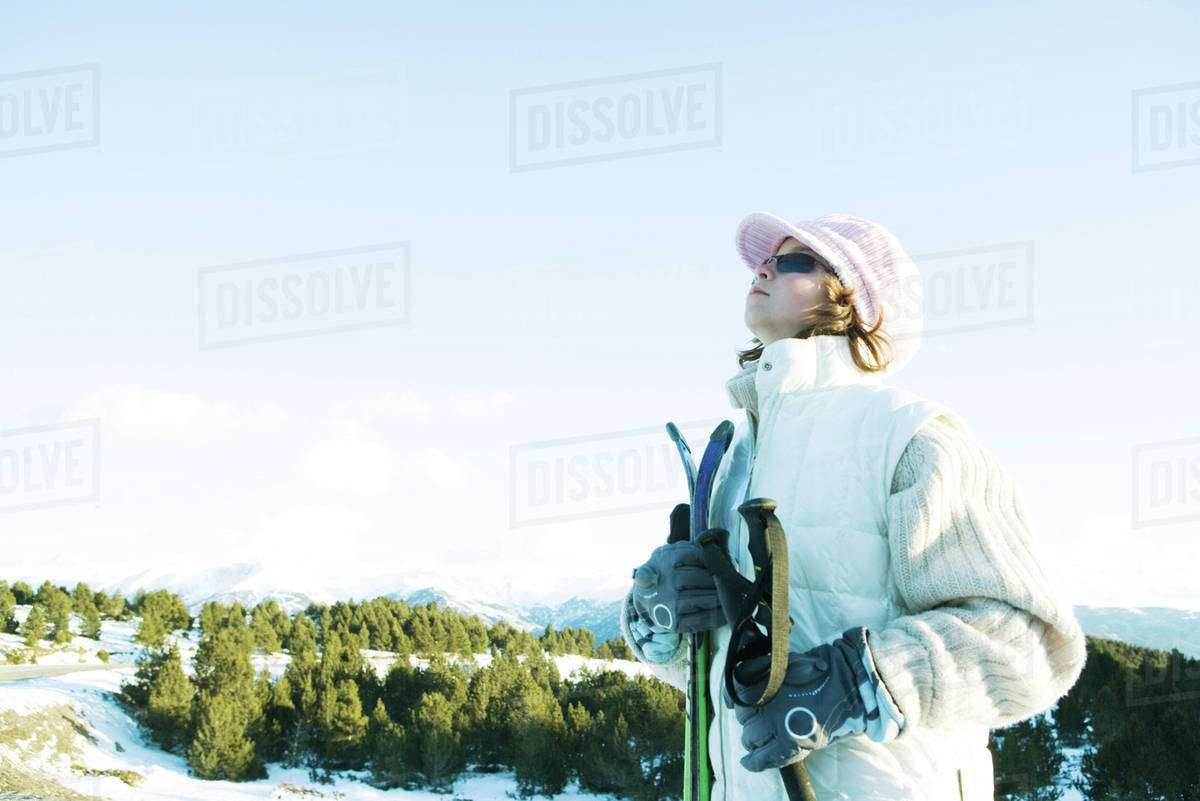 Young skier standing, looking up, side view - Stock Photo - Dissolve