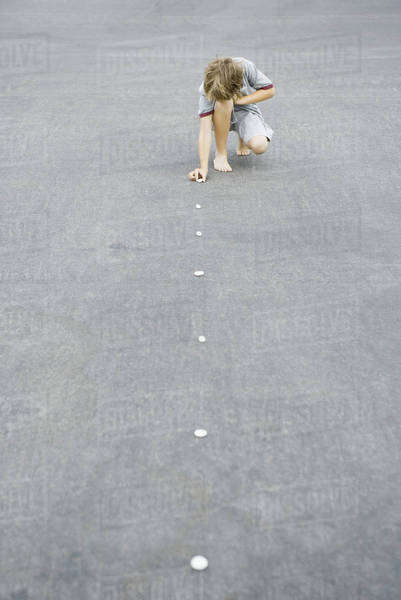 Child crouching on the ground, lining up pebbles, full length - Stock ...