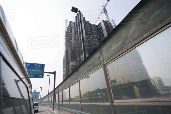 Wall on side of road, viewed from vehicle, high rise under construction ...
