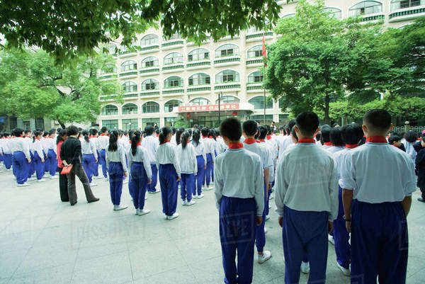 Large group of students in uniform standing in square, rear view ...
