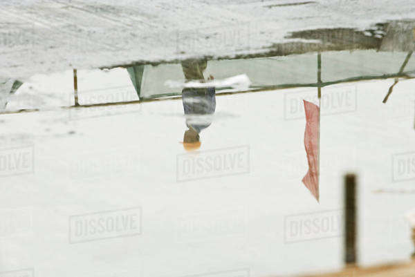 Construction worker at construction site, reflected in puddle of water ...