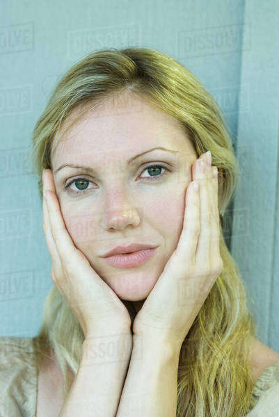 Woman holding face in hands, looking at camera, portrait - Royalty-free ...