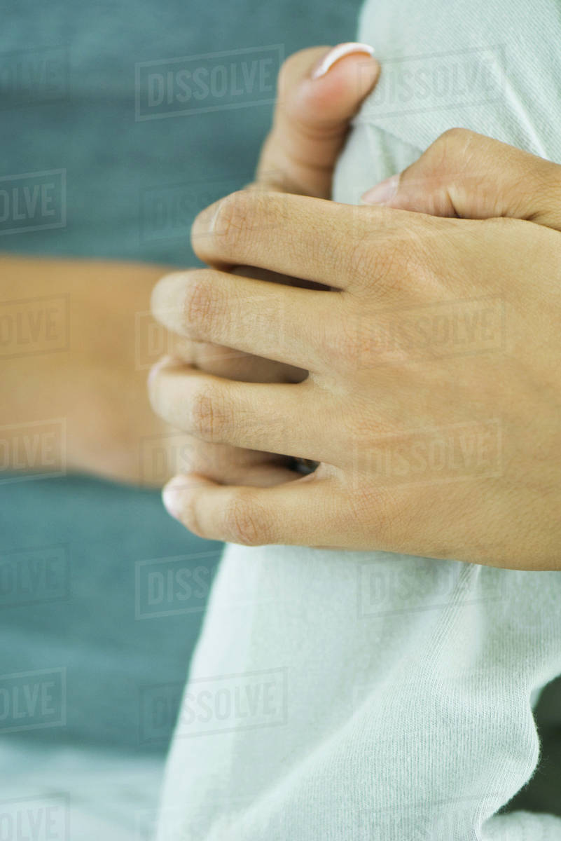 Hands clasping arm, cropped view - Royalty-free Stock Photo | Dissolve