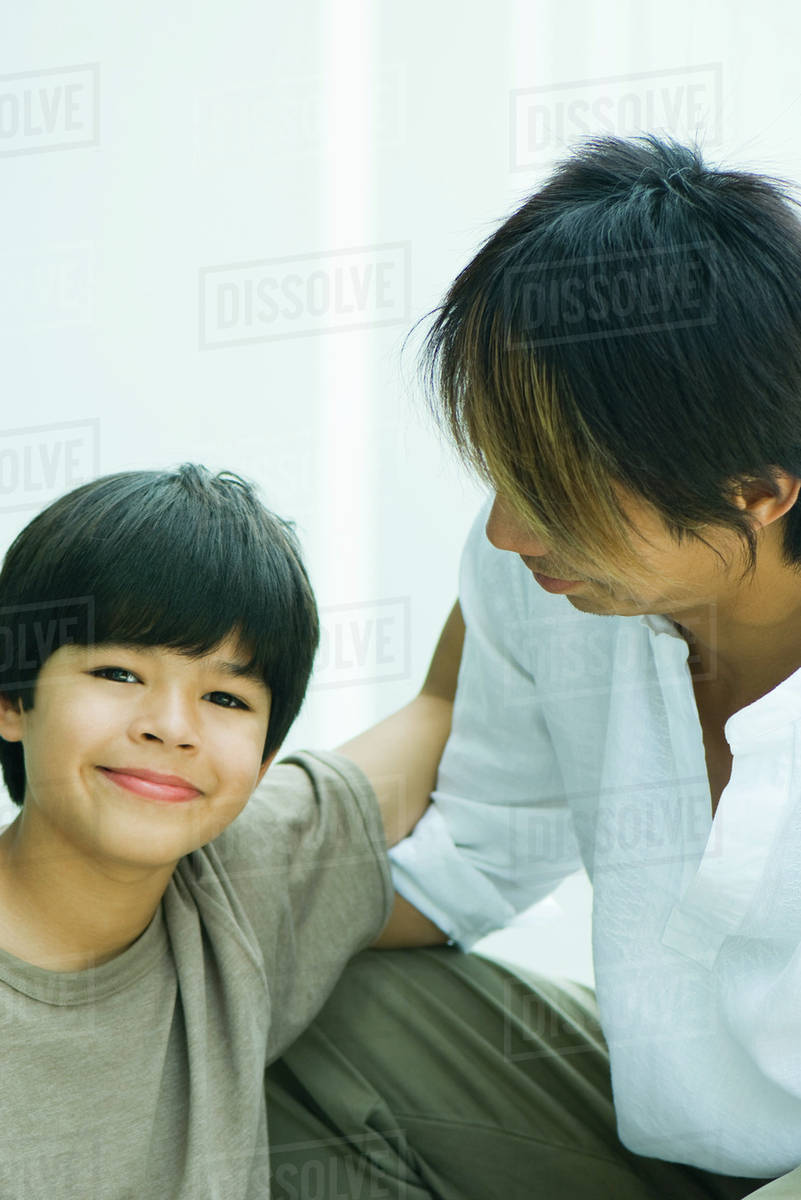 Boy with arm around father's shoulder, smiling at camera, portrait ...