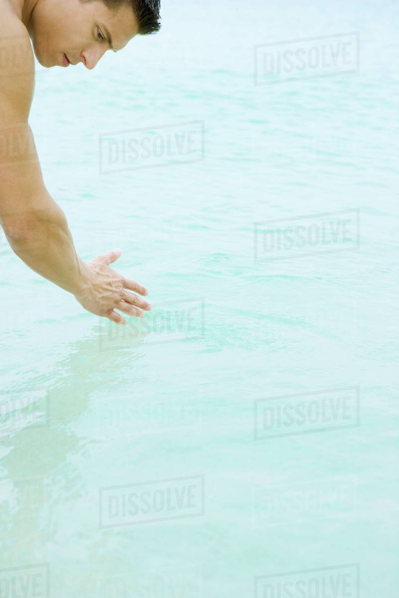 Man bending over, touching water, cropped view - Royalty-free Stock ...