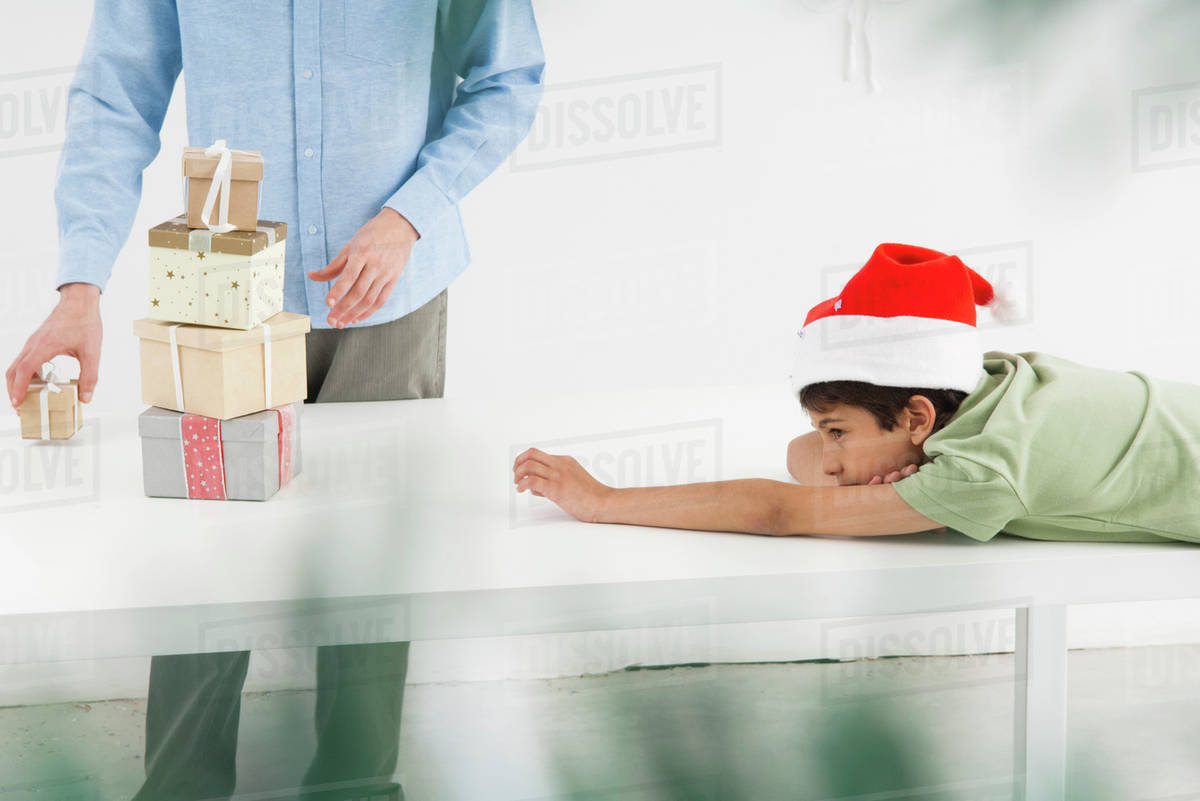 Boy looking longingly at stack of Christmas presents - Stock Photo ...