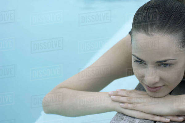 Woman lying next to pool, resting head on arms, looking away - Royalty ...