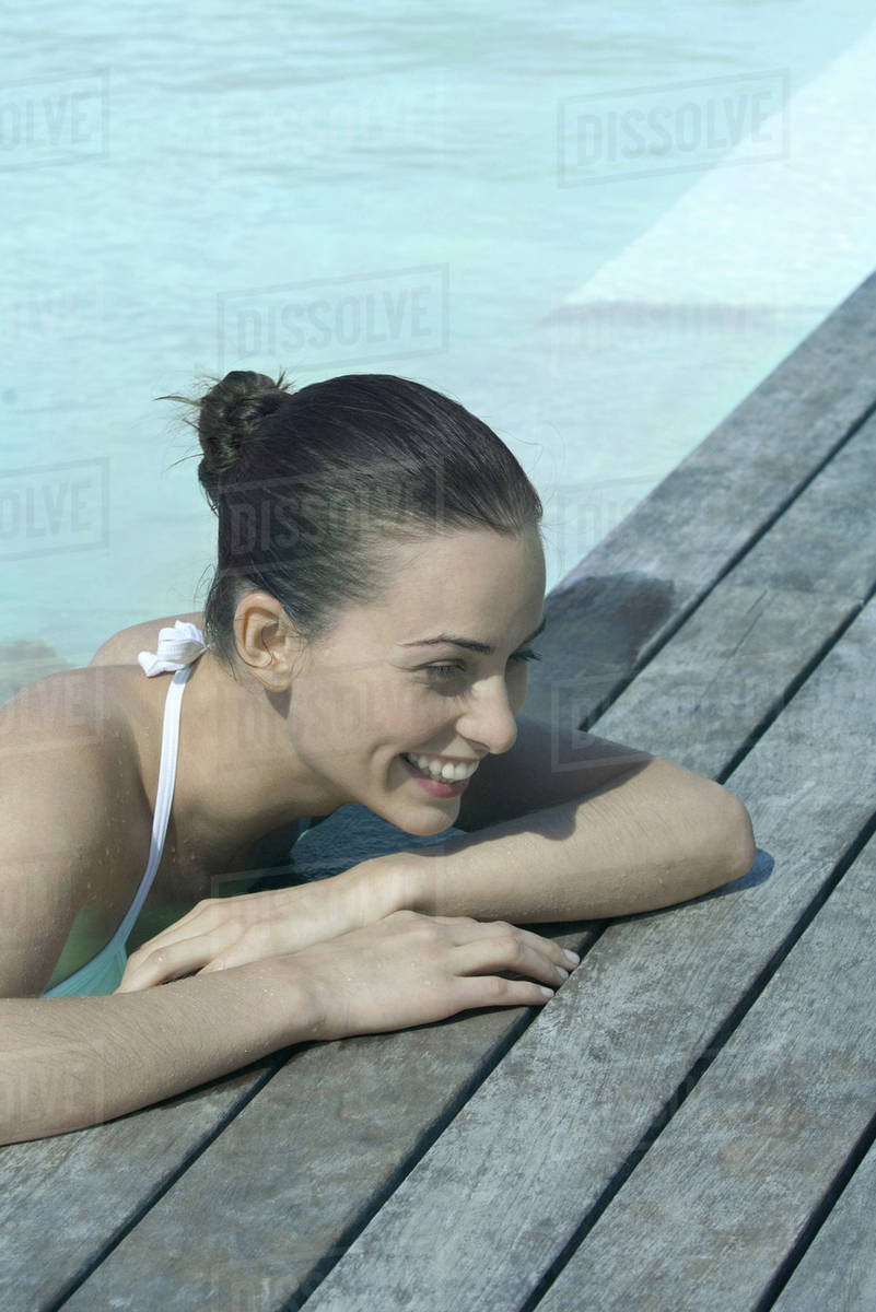 Young woman leaning on poolside, smiling - Royalty-free Stock Photo ...