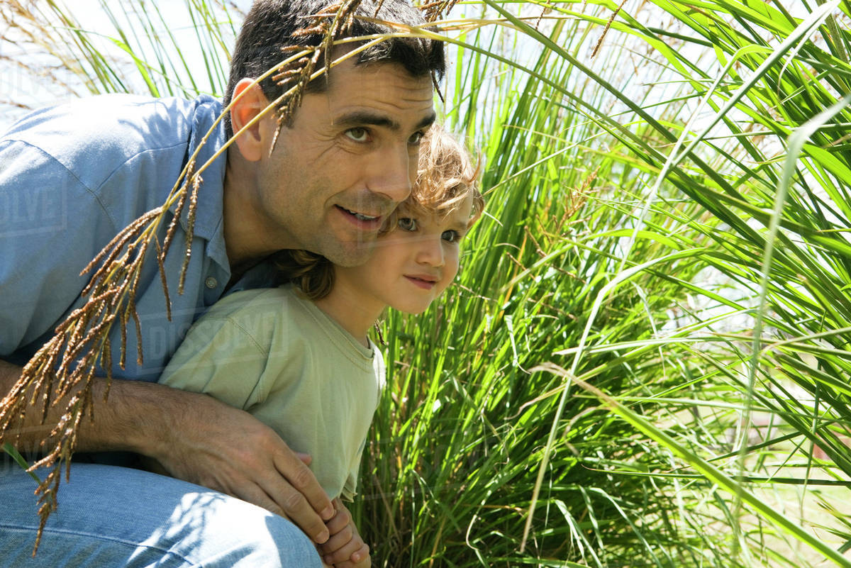 Father and son hiding in tall grass - Stock Photo - Dissolve