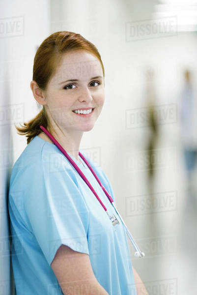 Nurse leaning against wall, portrait - Stock Photo - Dissolve