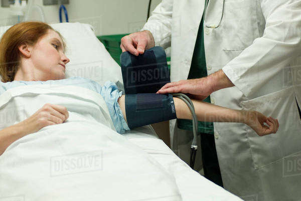 Doctor putting blood pressure cuff on patient in hospital - Royalty ...