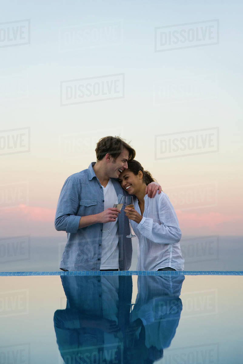 Couple embracing at edge of infinity pool, enjoying champagne - Royalty ...