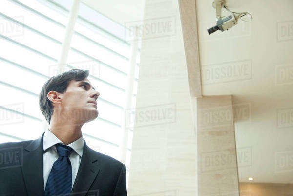 Businessman looking up at security camera - Royalty-free Stock Photo ...