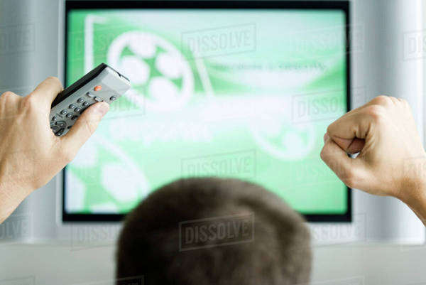 Person watching flat screen television, hands raised in air, cropped ...